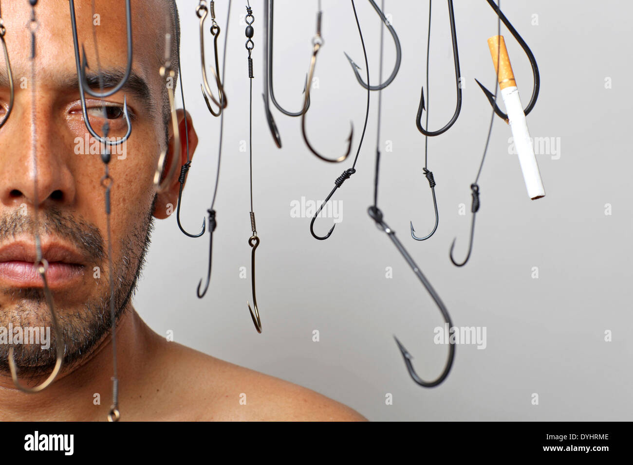 Man Surrounded by Hanging Fish Hooks Looking at Cigarette on Fish Hook ...