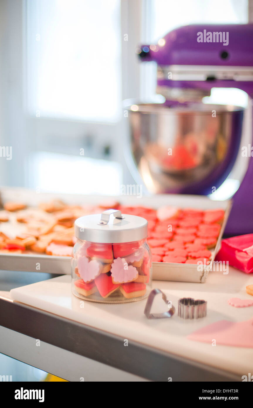 Jar Filled with Heart-Shaped Cookies next to Cookie Cutter and Mixer ...
