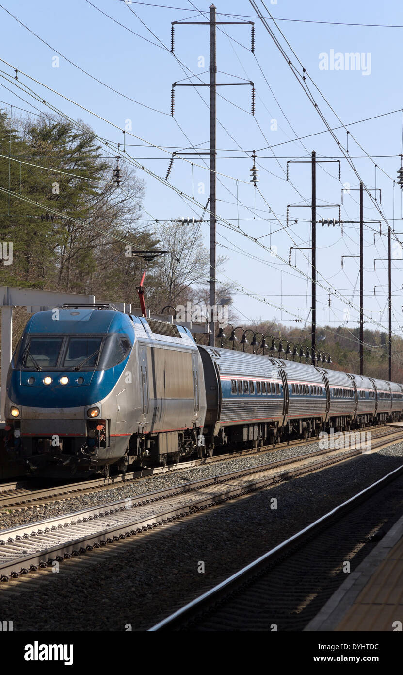 An electric train pulling into a station on rail road tracks Stock ...