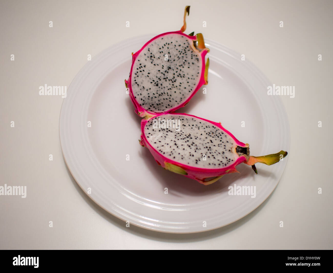 pitaya fruit cut open in a white plate with white background seen from ...