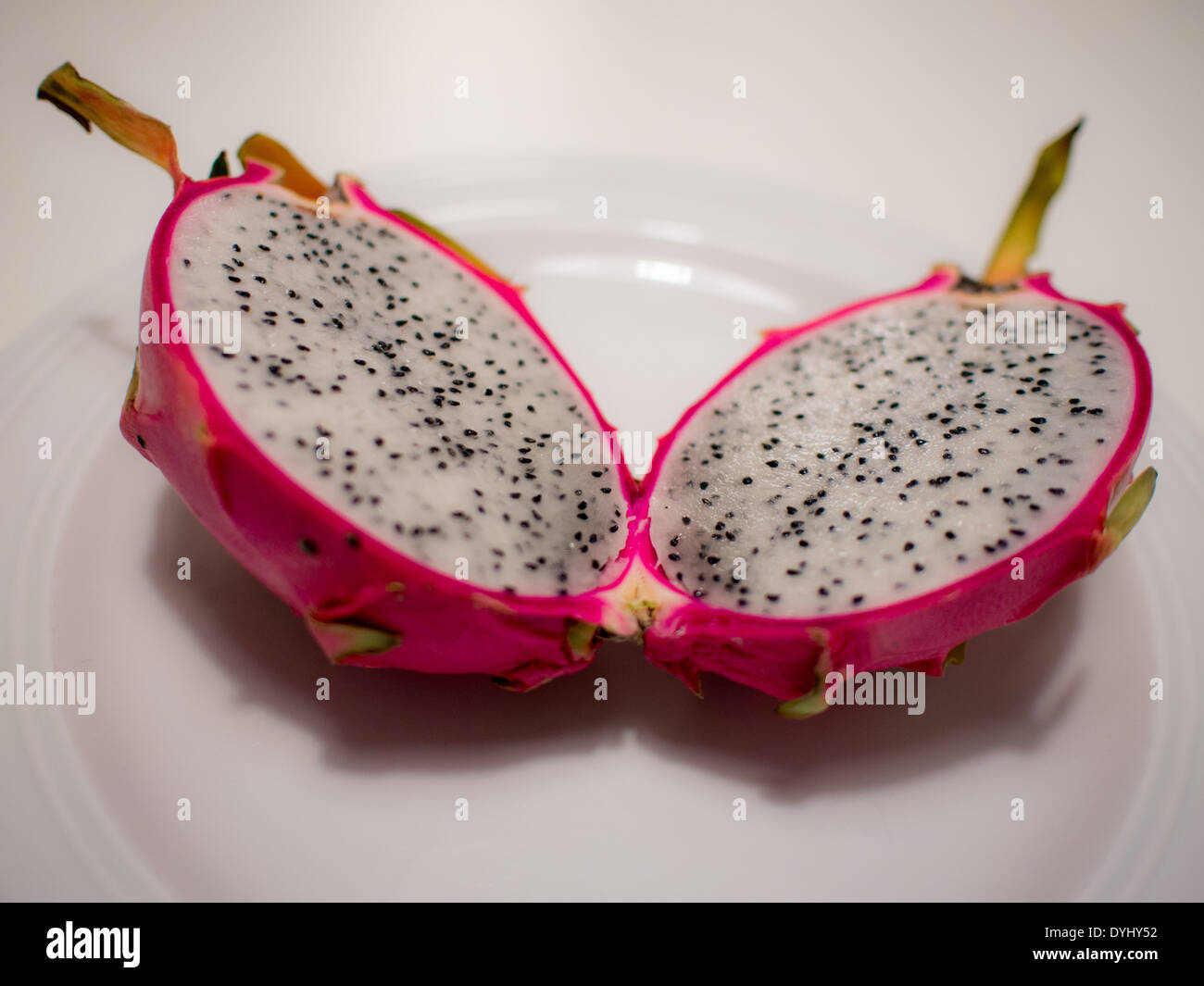 pitaya fruit cut open in a white plate with white background seen from ...