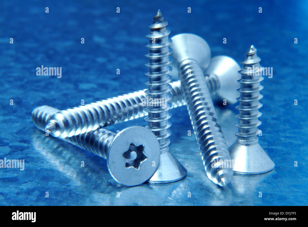 Security screws on blue metal background Stock Photo - Alamy