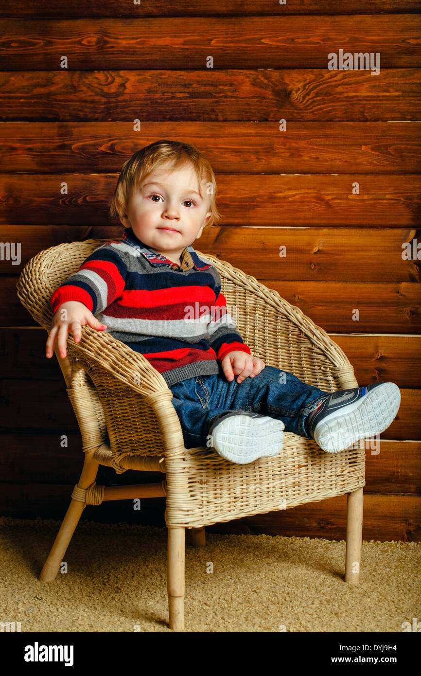 Little boy sitting in a wicker chair in a wooden house Stock Photo - Alamy