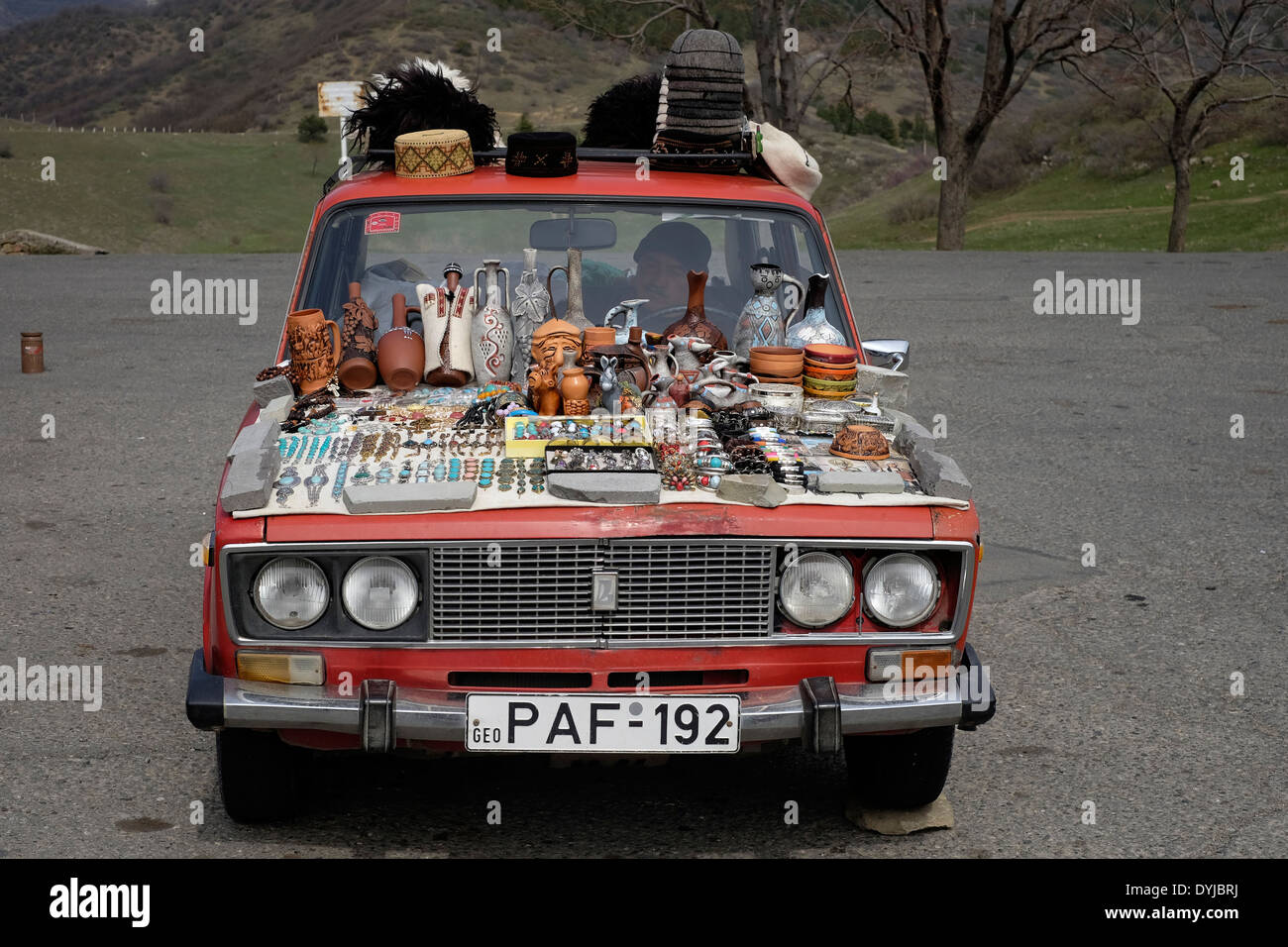 A vendor's items are displayed on the hood of a Lada car manufactured ...