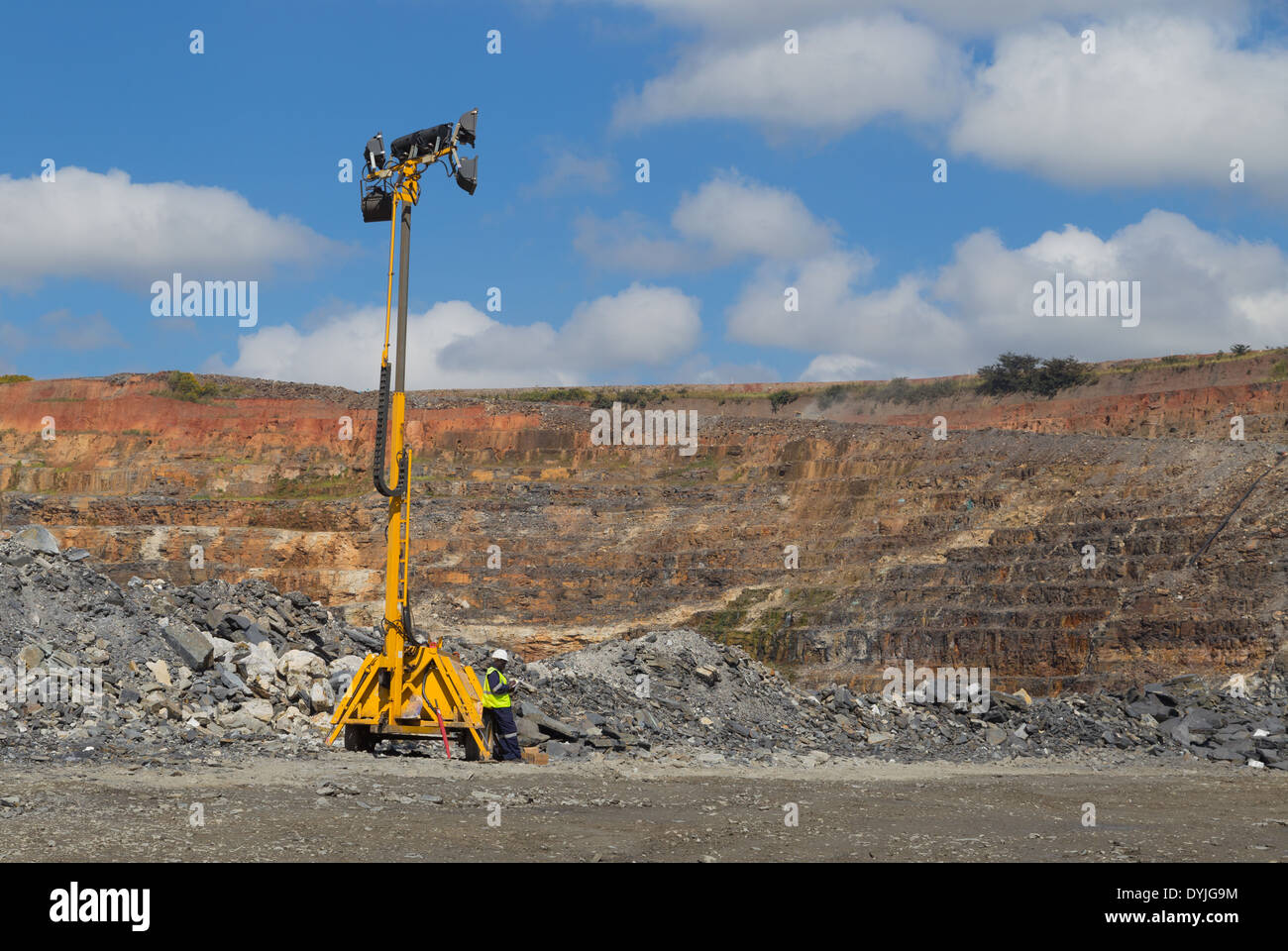 A grade controller leans against a lighting plant in a large open cast ...