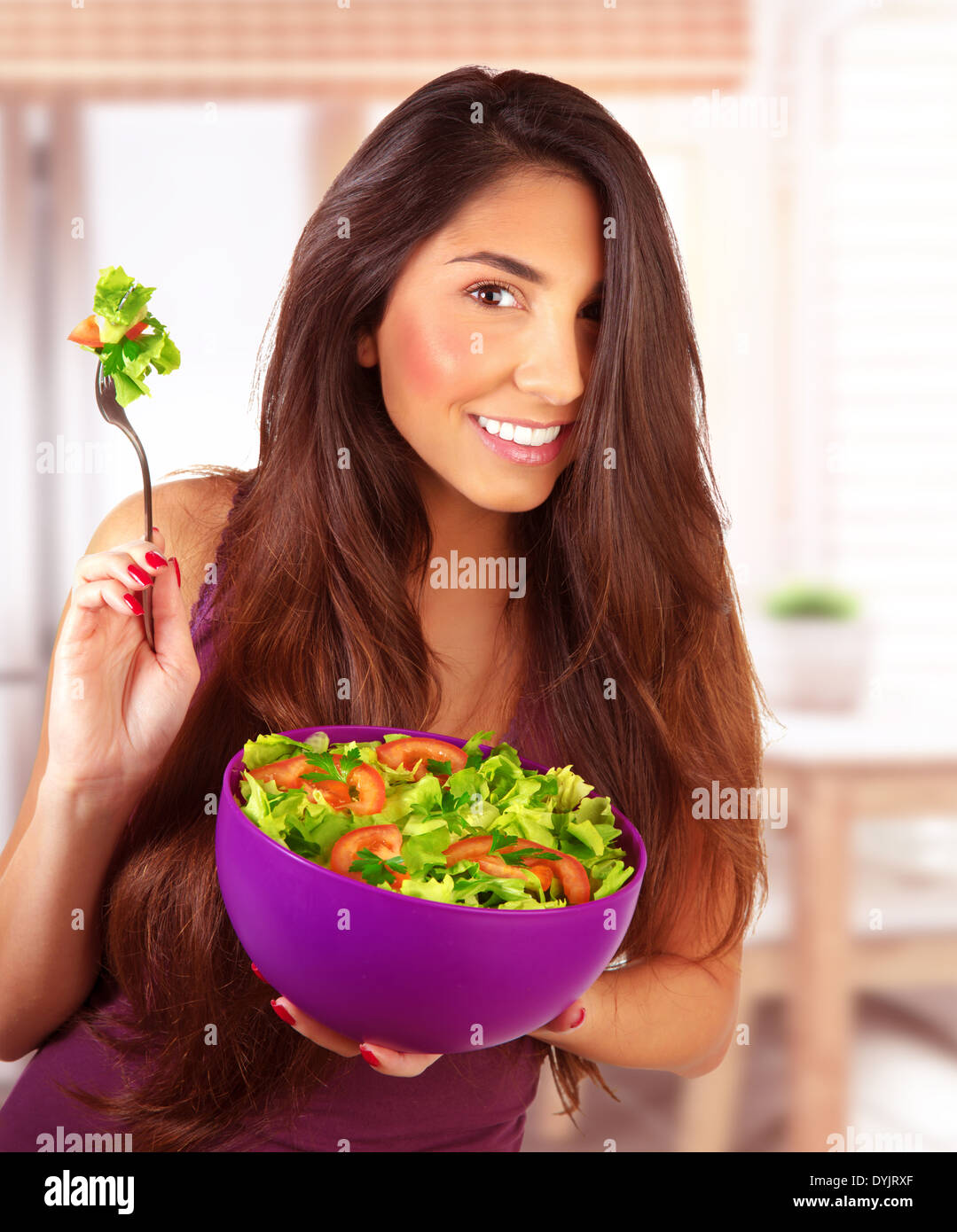 Sportive girl eating fresh vegetarian salad at home in the kitchen ...
