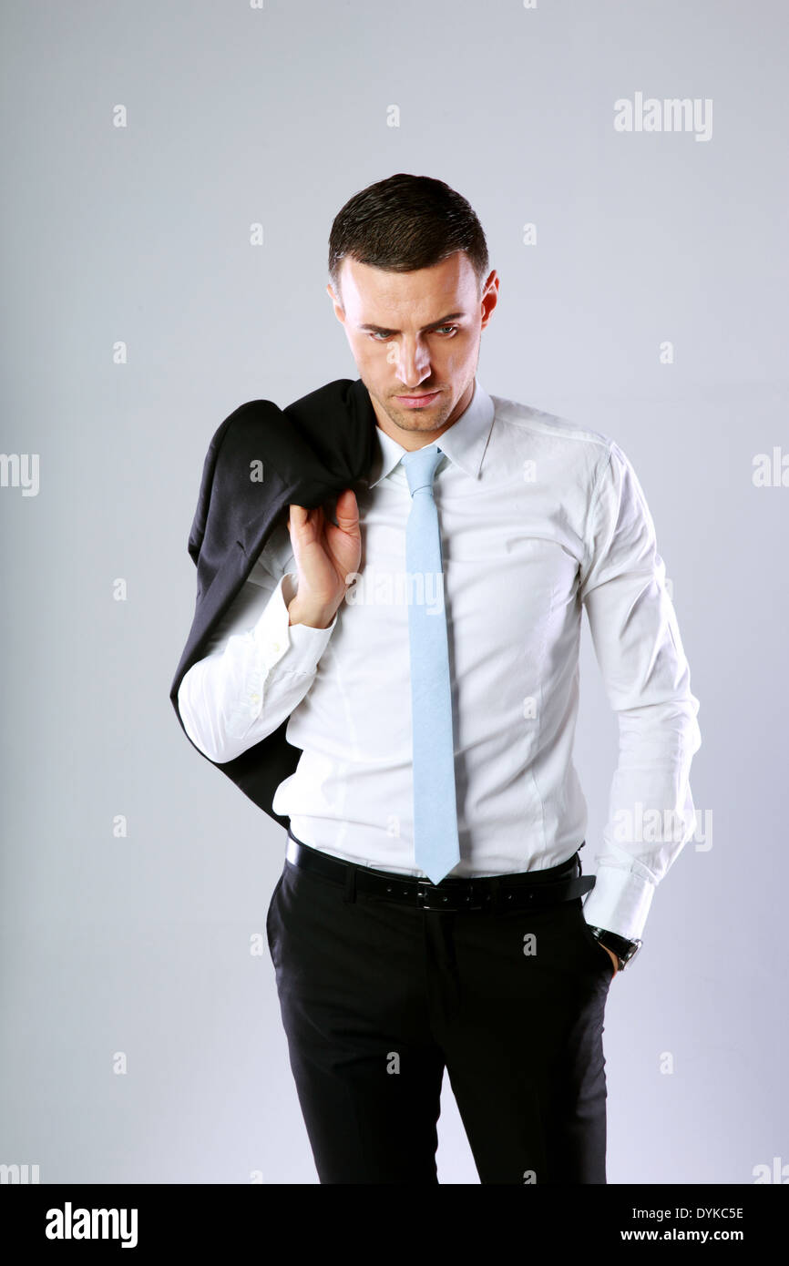 Pensive business man holding jacket on shoulder on gray background ...
