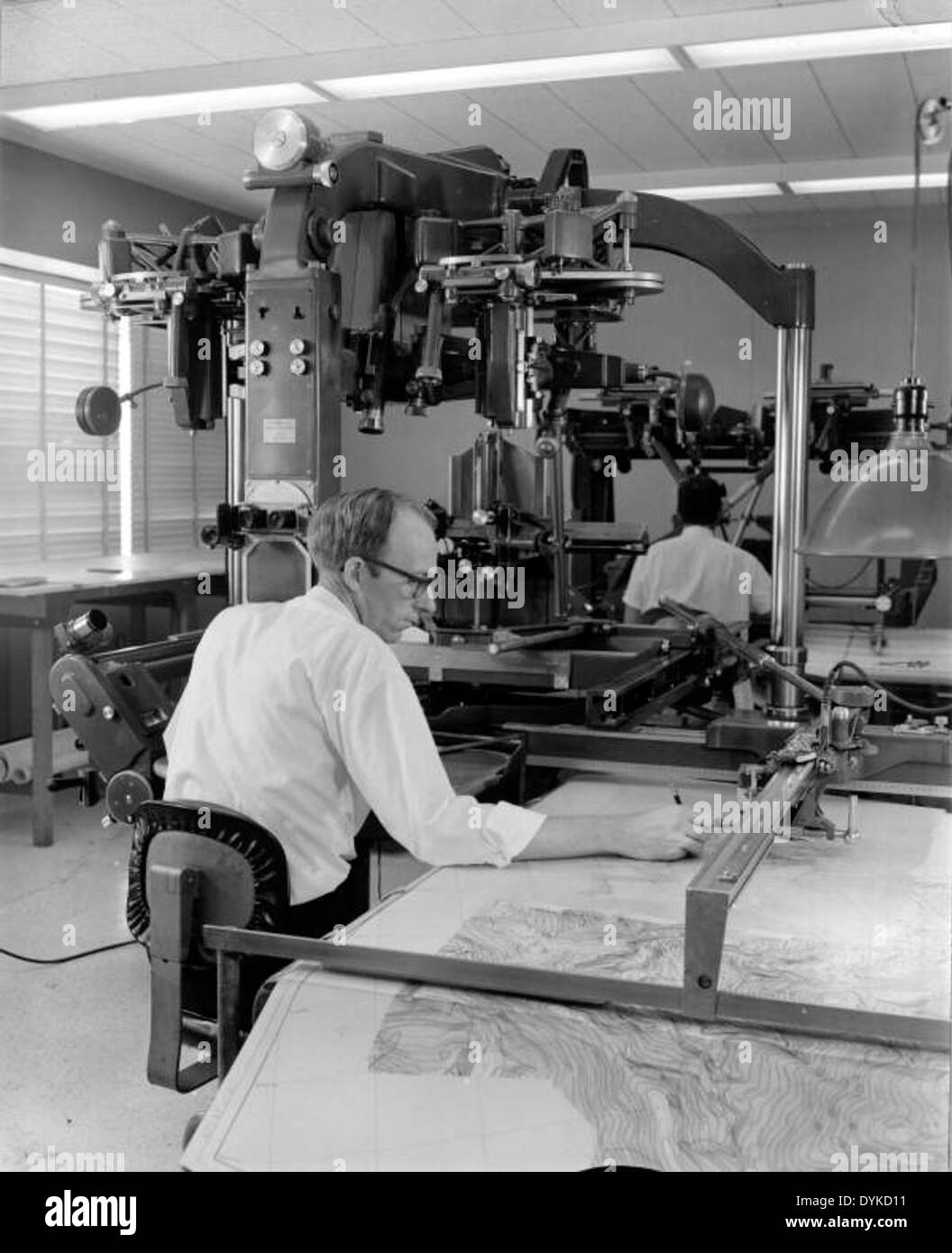 A man operates a stereo mapping machine for topographic maps in Dade ...