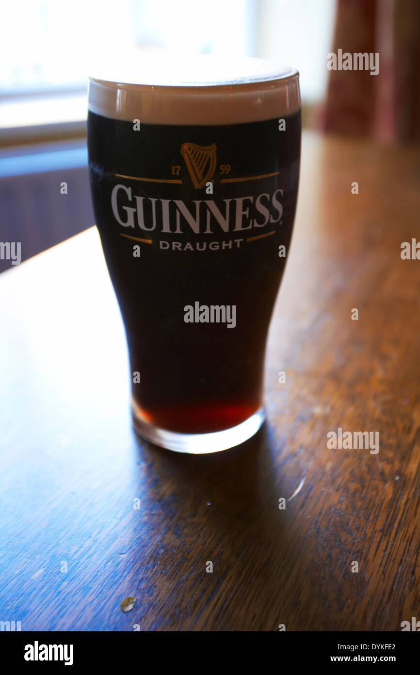 A pint of Guiness beer on a table in an Irish Pub Stock Photo - Alamy