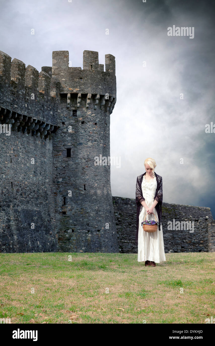 a woman in a white period dress is standing in front of a castle Stock ...