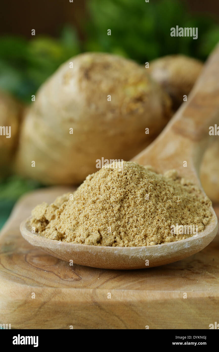 ground ginger in a wooden spoon, fresh root in the background Stock ...