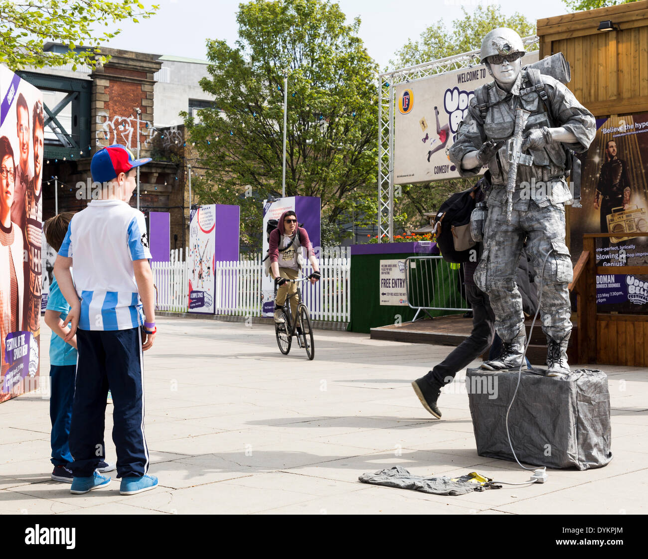 London, UK. 21st Apr, 2014. Two children observe a busker performing in ...