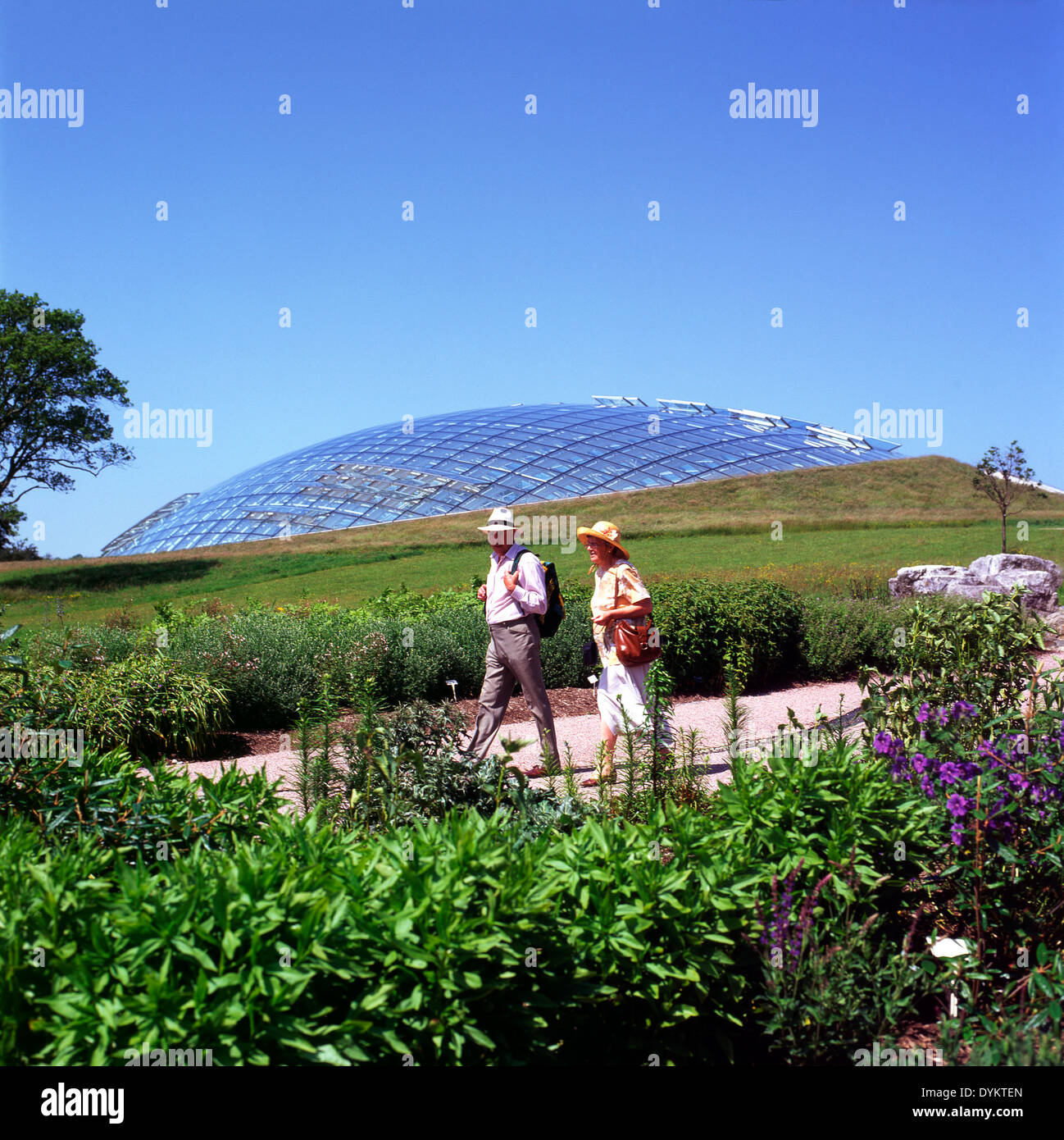 Two senior visitors people walking on a path outside the Great Glass ...