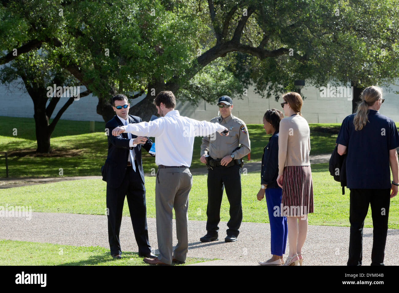 Security team uses metal detector wand on people and media attending ...