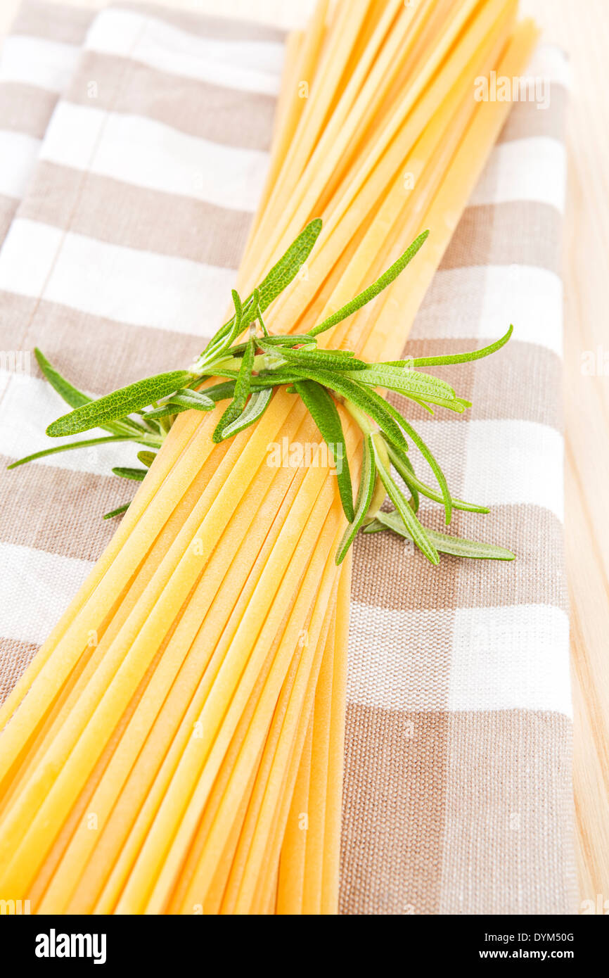Bunch of spaghetti tied up with green rosemary herb. Culinary cooking ...