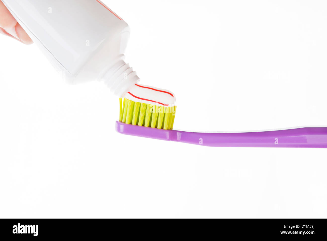 Red and white striped toothpaste on green and purple toothbrush ...