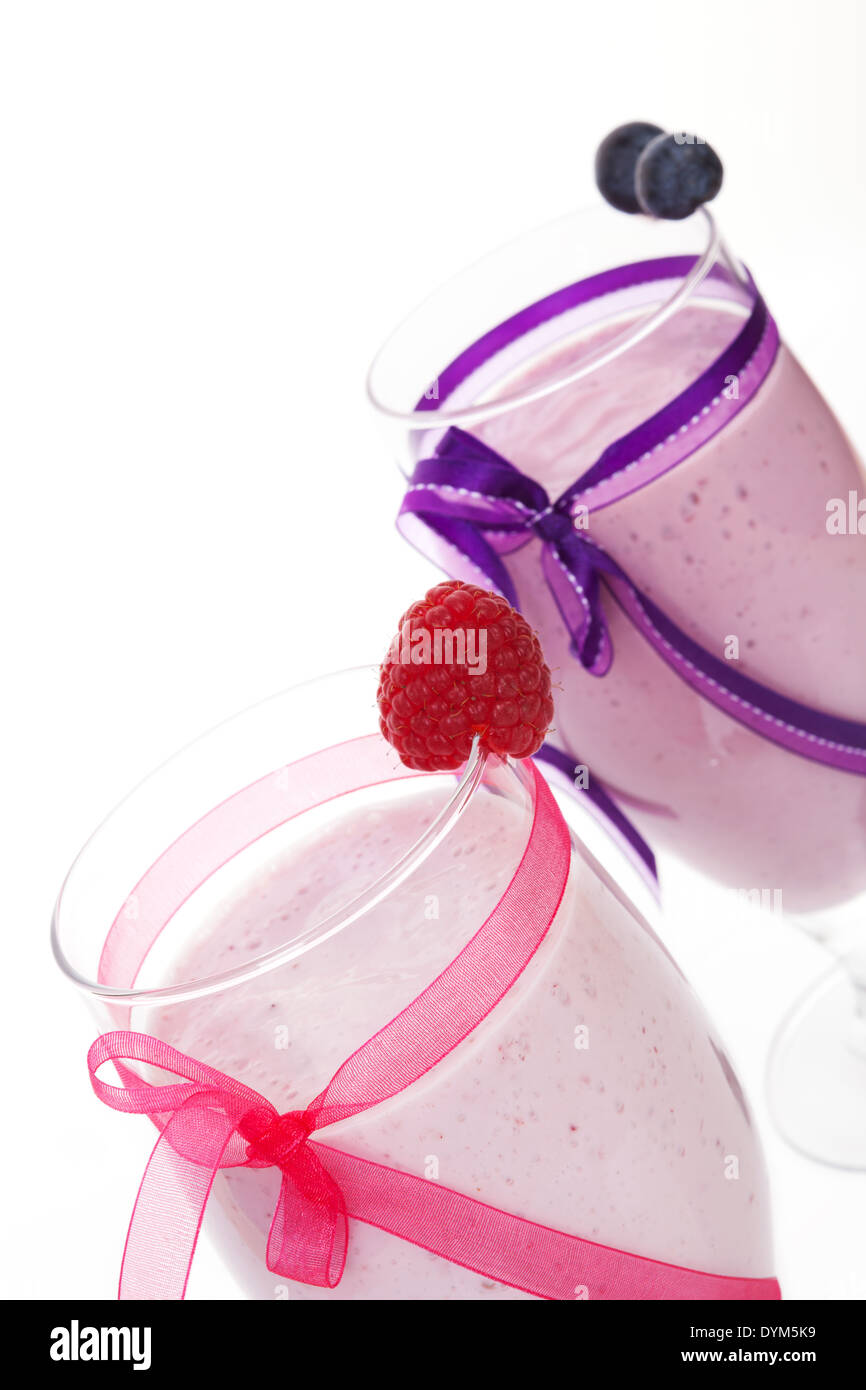 Raspberry and blueberry fruit milkshakes decorated with ribbon isolated ...
