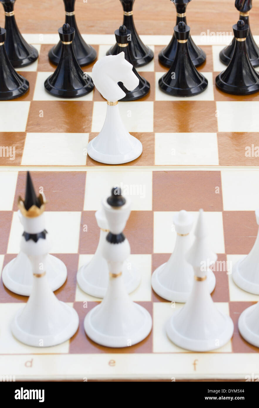 white knight in front of black chess Stock Photo - Alamy