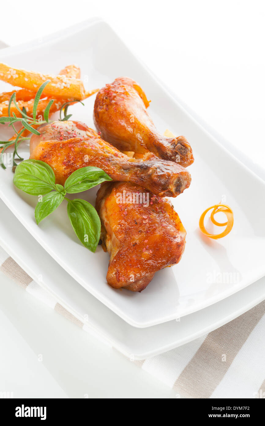 Delicious grilled chicken legs on white plate with fresh herbs and ...