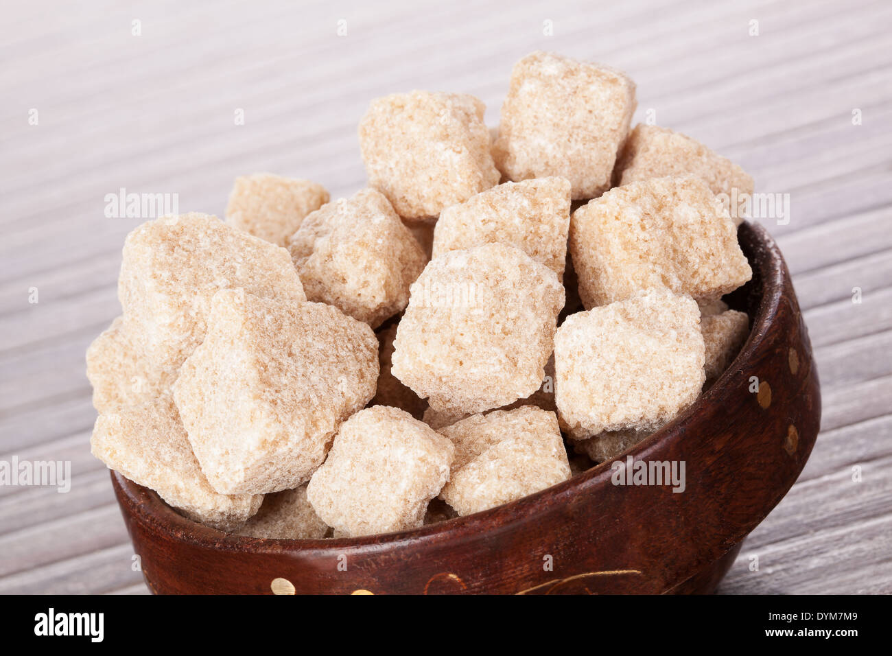 Brown sugar cubes detail in wooden round bowl on brown background ...