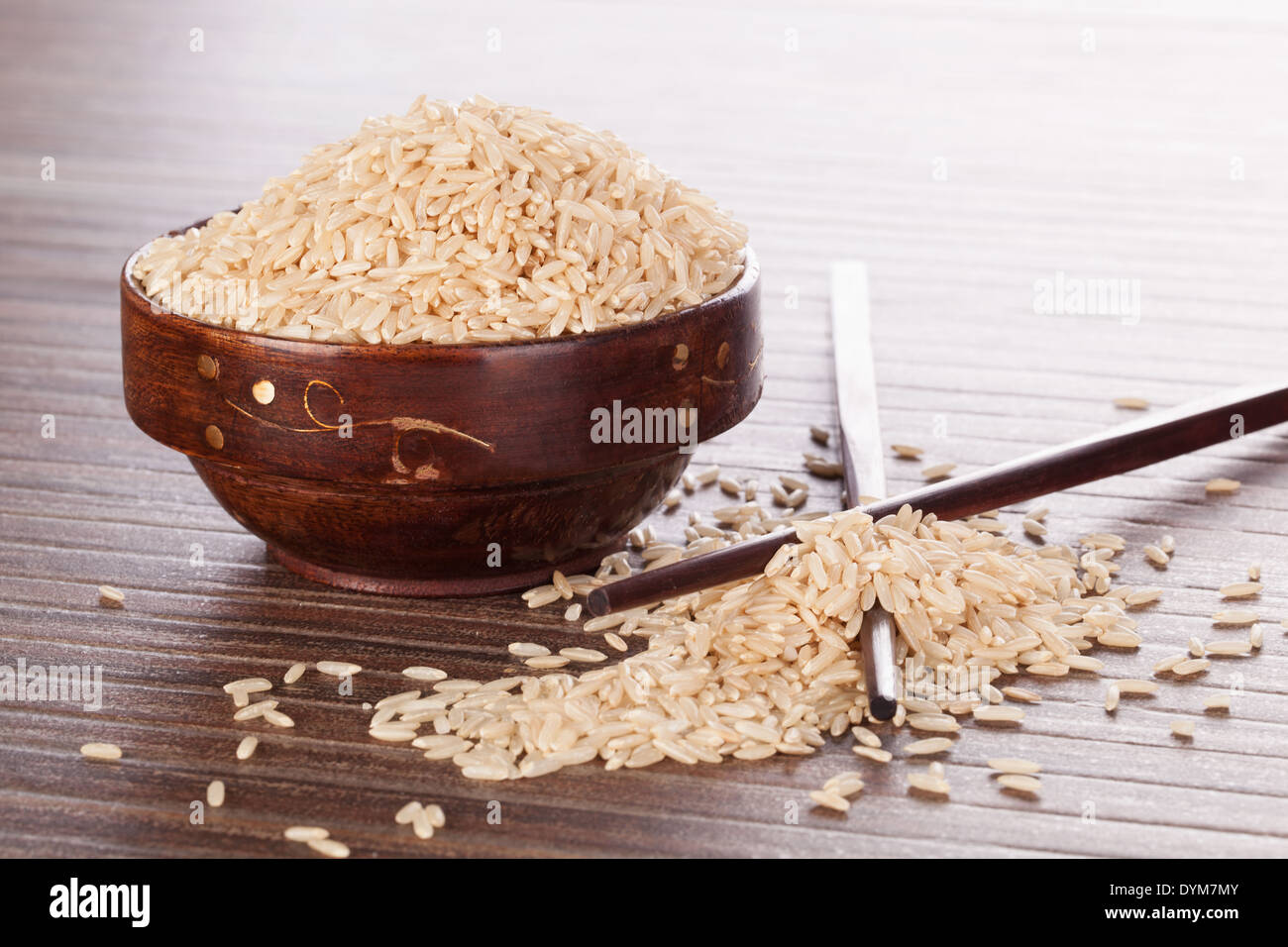 Natural brown rice background. Raw uncooked rice in wooden bowl with ...