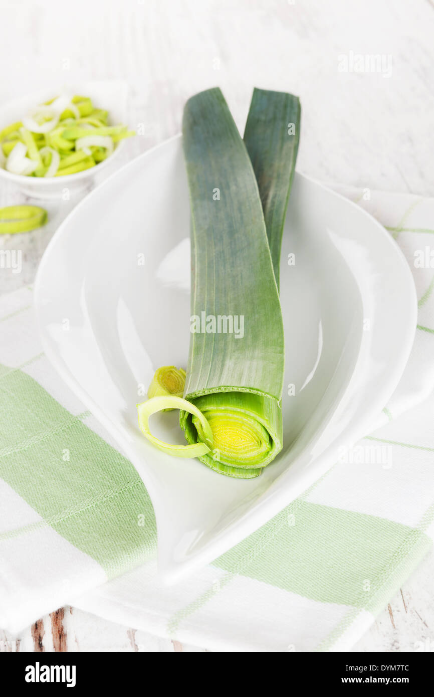 Delicious leek background. Raw leek on white plate on white wooden ...