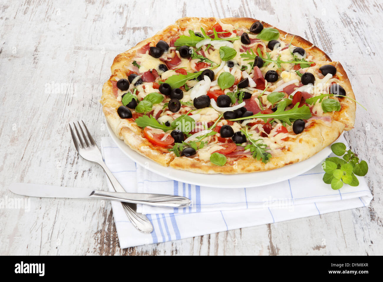 Colorful pizza with black olives and fresh herbs ham and melted cheese ...