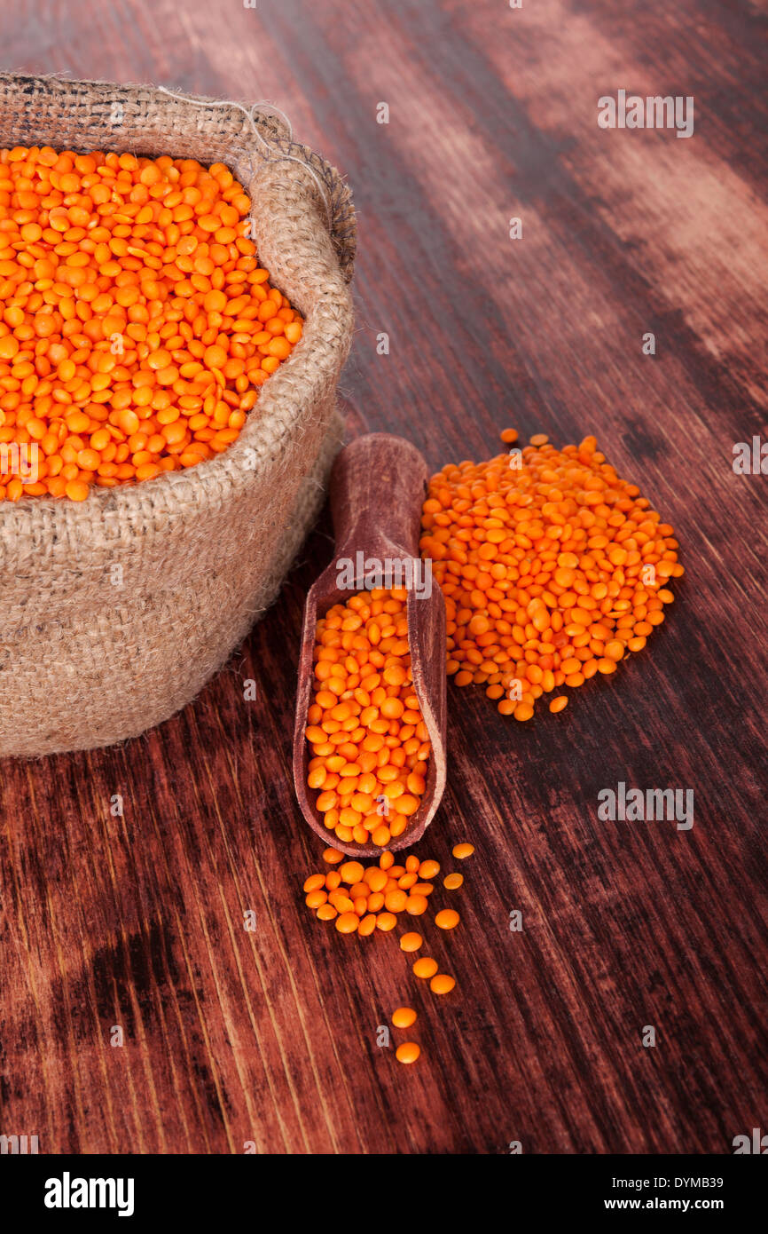 Red lentils in brown burlap sack with wooden spoon on dark wooden ...