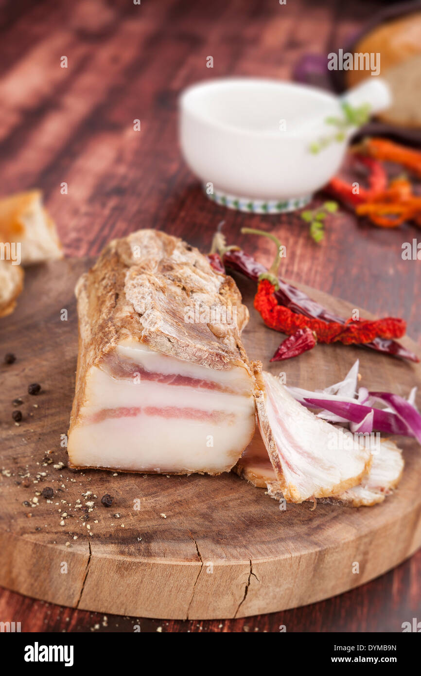 Traditional bacon eating. Big fat bacon piece, onion, herbs on wooden ...