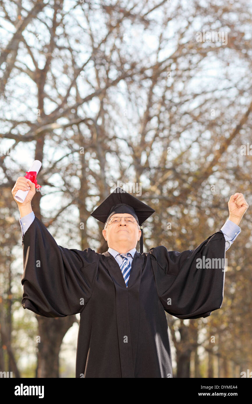 Mature college graduate gesturing success outdoors Stock Photo - Alamy