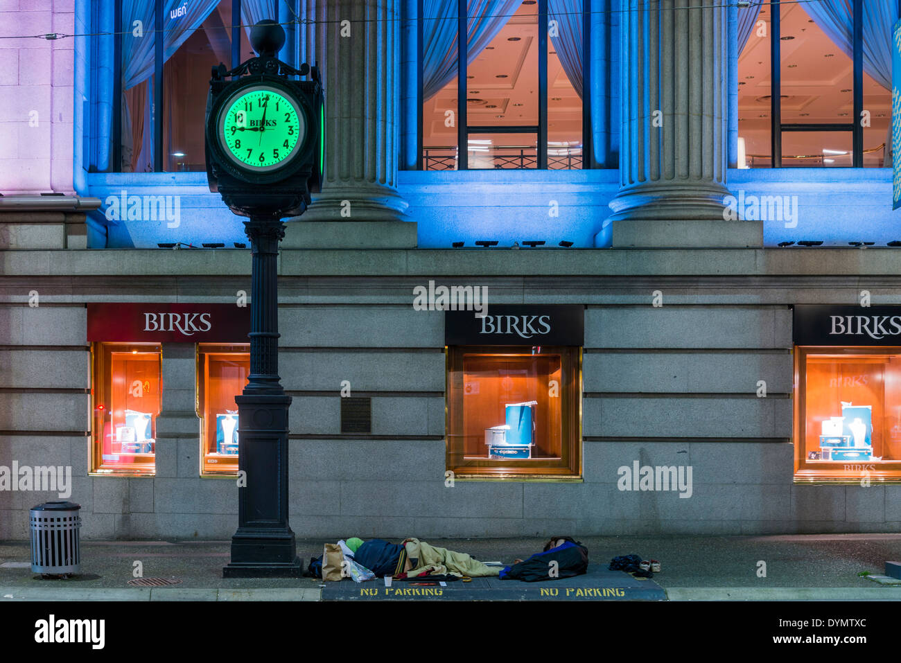 A couple sleep on the sidewalk on Granville street at night, downtown ...