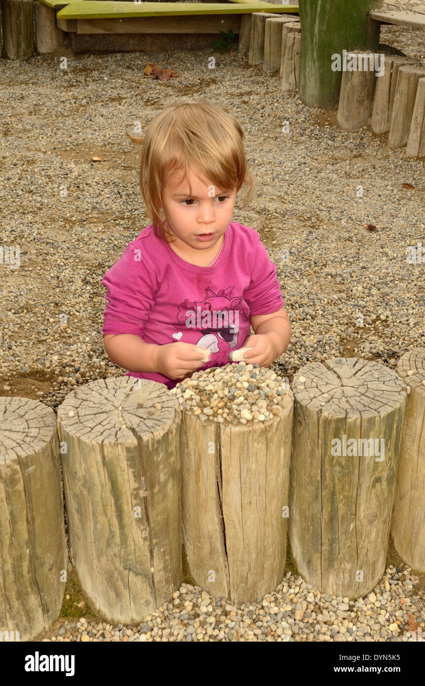 Little girl playing with pebbles at the playground Stock Photo - Alamy