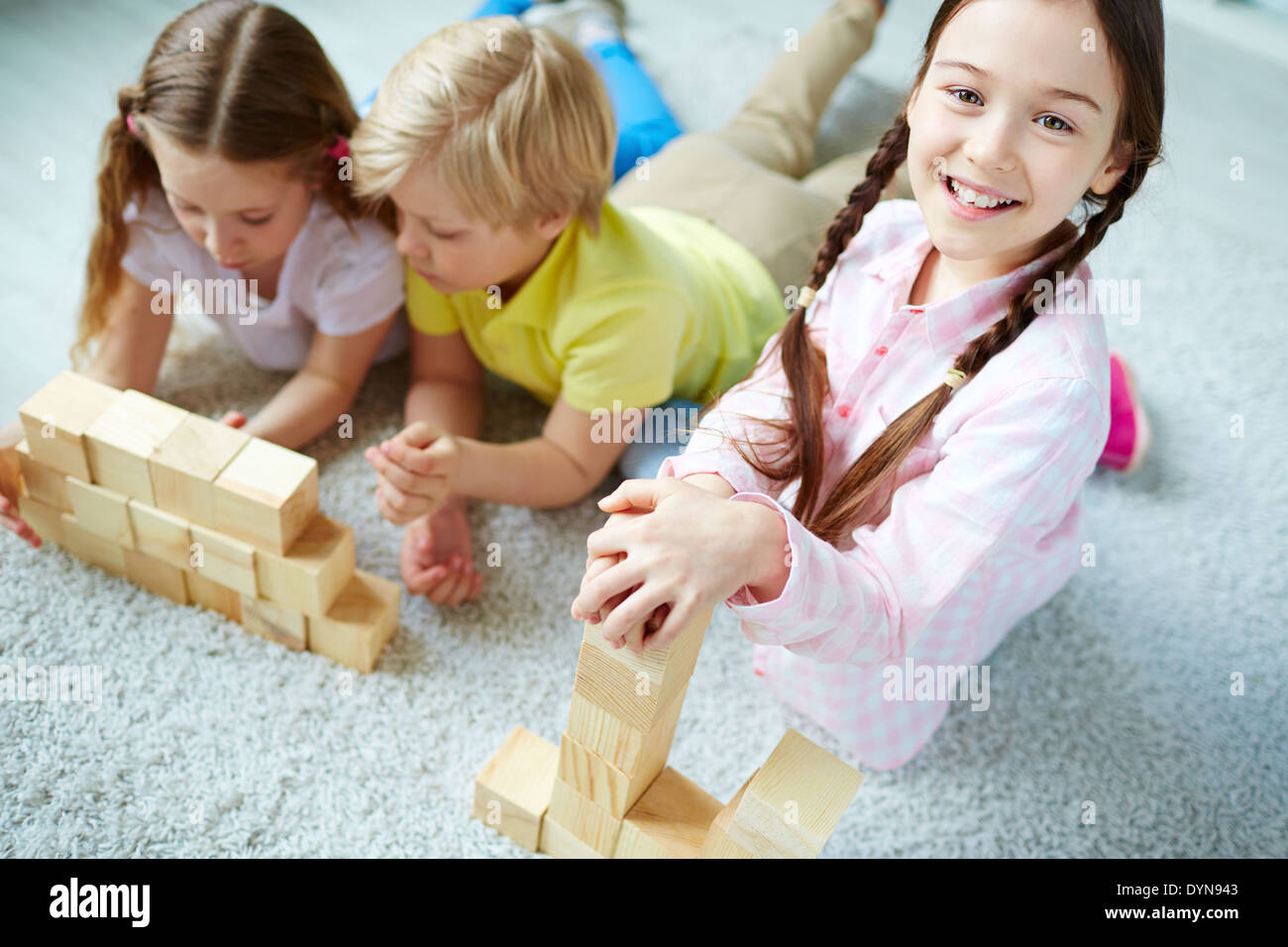 Three little friends playing with wooden bricks, happy girl looking at ...