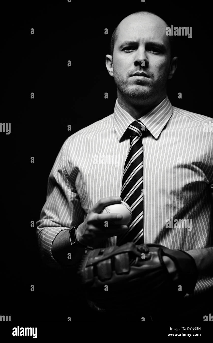 Portrait of serious businessman with baseball ball and glove looking at ...