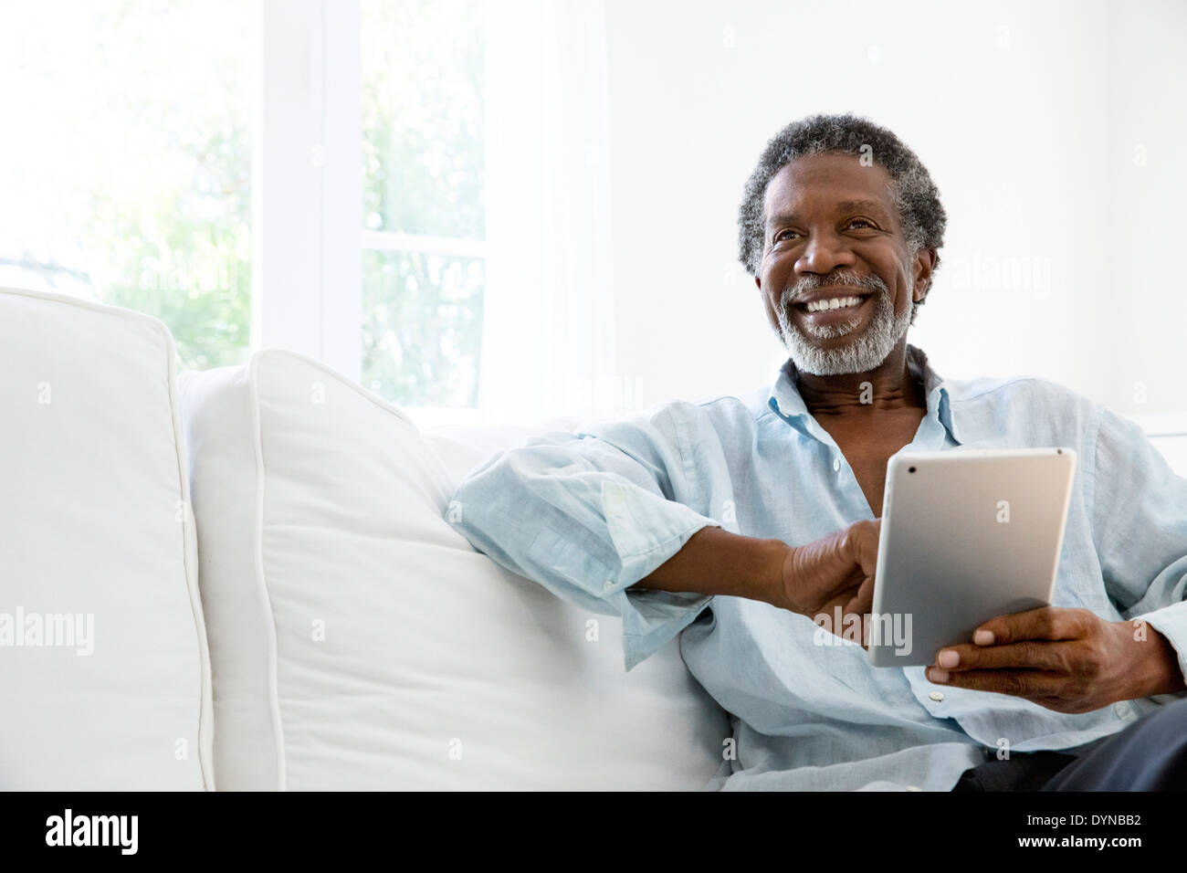 Senior man using digital tablet on sofa Stock Photo - Alamy