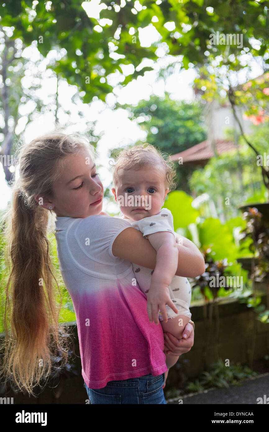 Caucasian girl carrying baby boy in tropical garden Stock Photo - Alamy