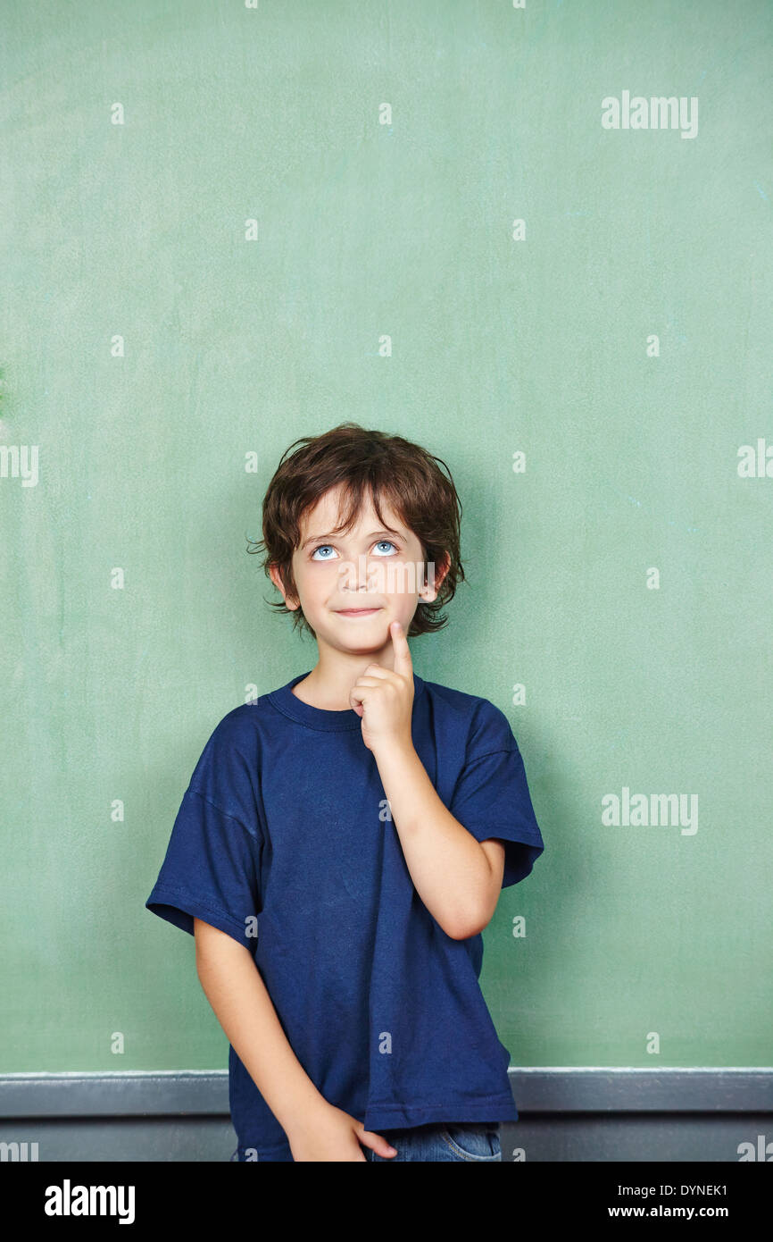 Elementary school student thinking in front of empty chalkboard Stock ...