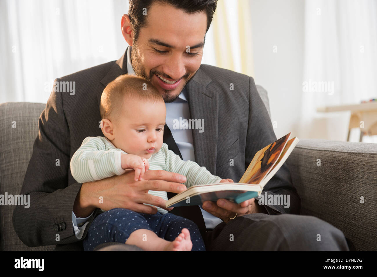Father reading to baby on sofa Stock Photo - Alamy