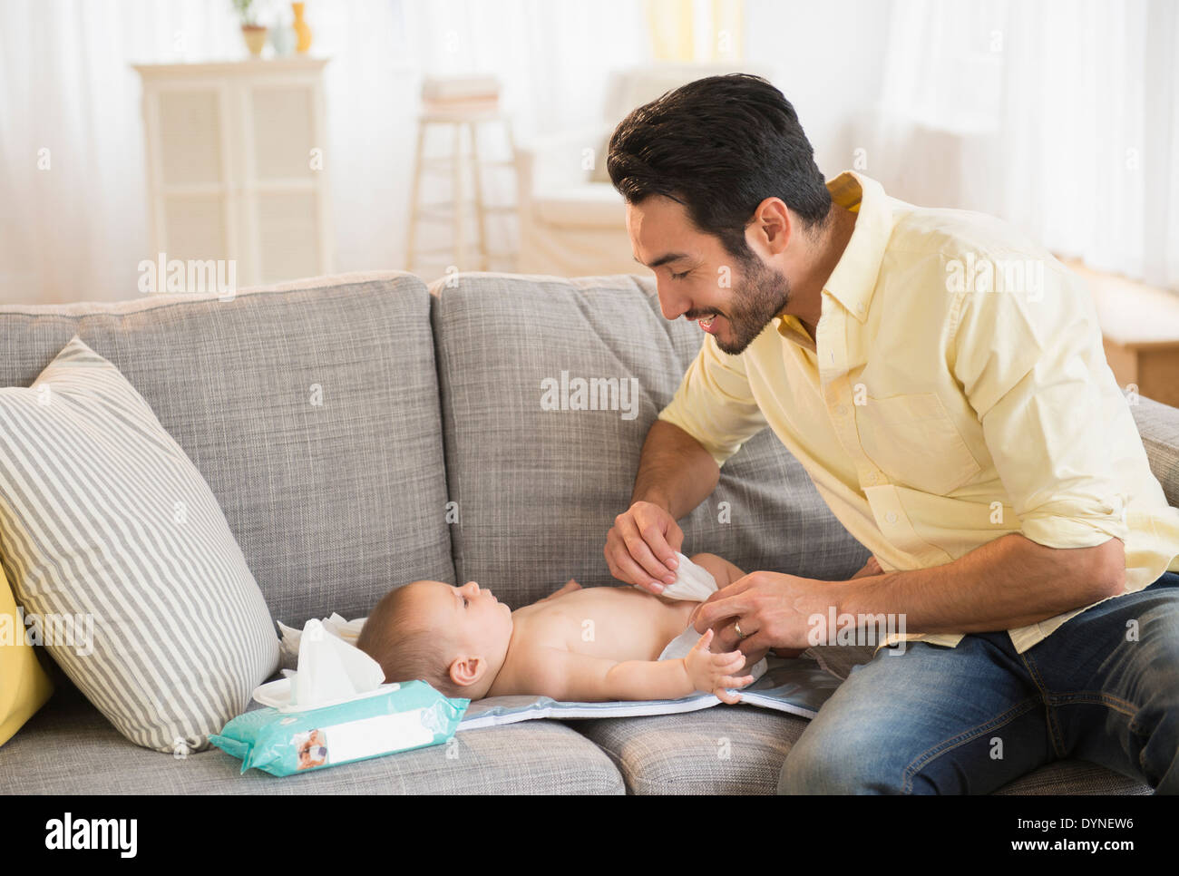 Father changing baby's diaper on sofa Stock Photo - Alamy