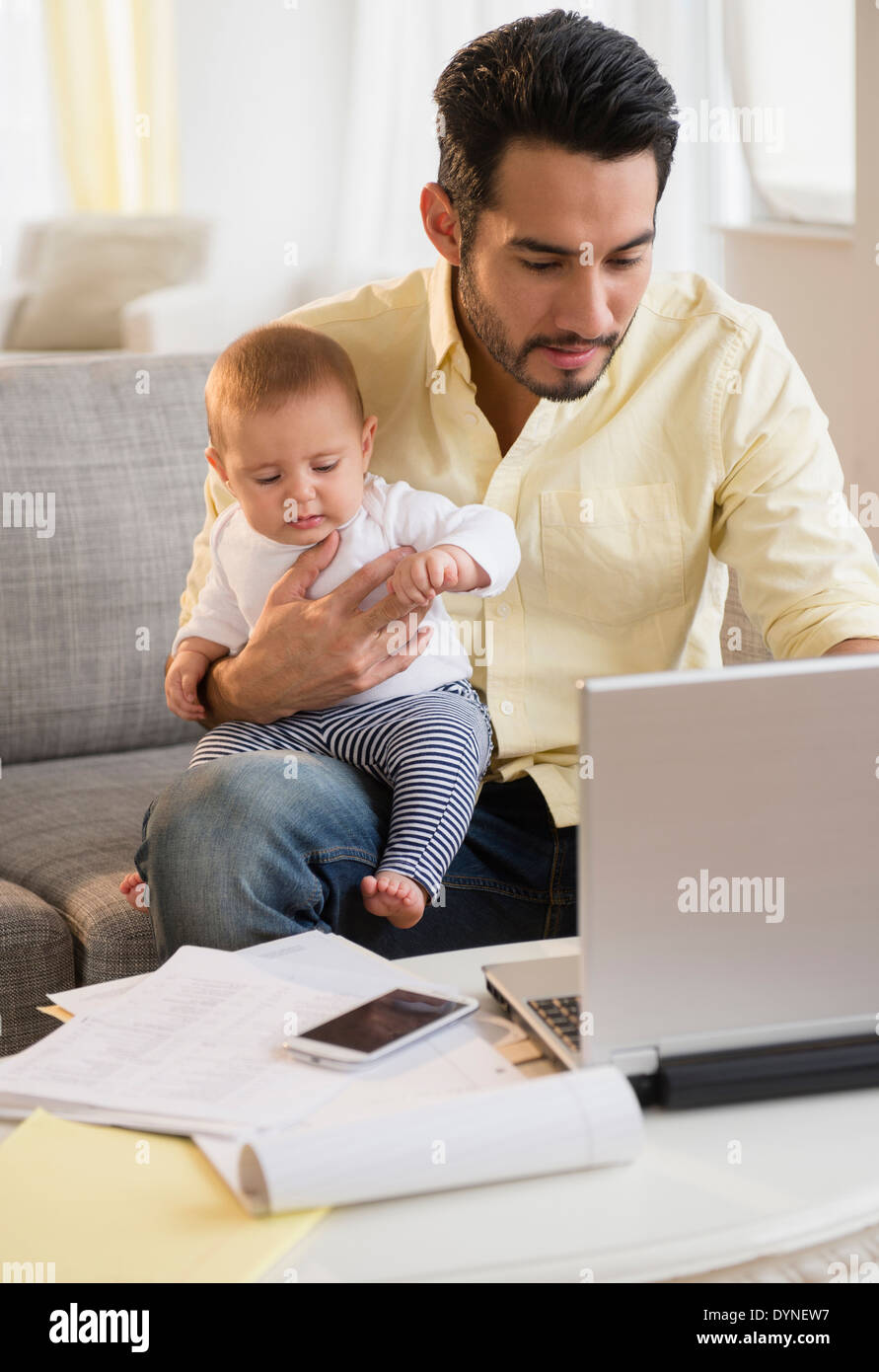 Father holding baby and using laptop Stock Photo - Alamy