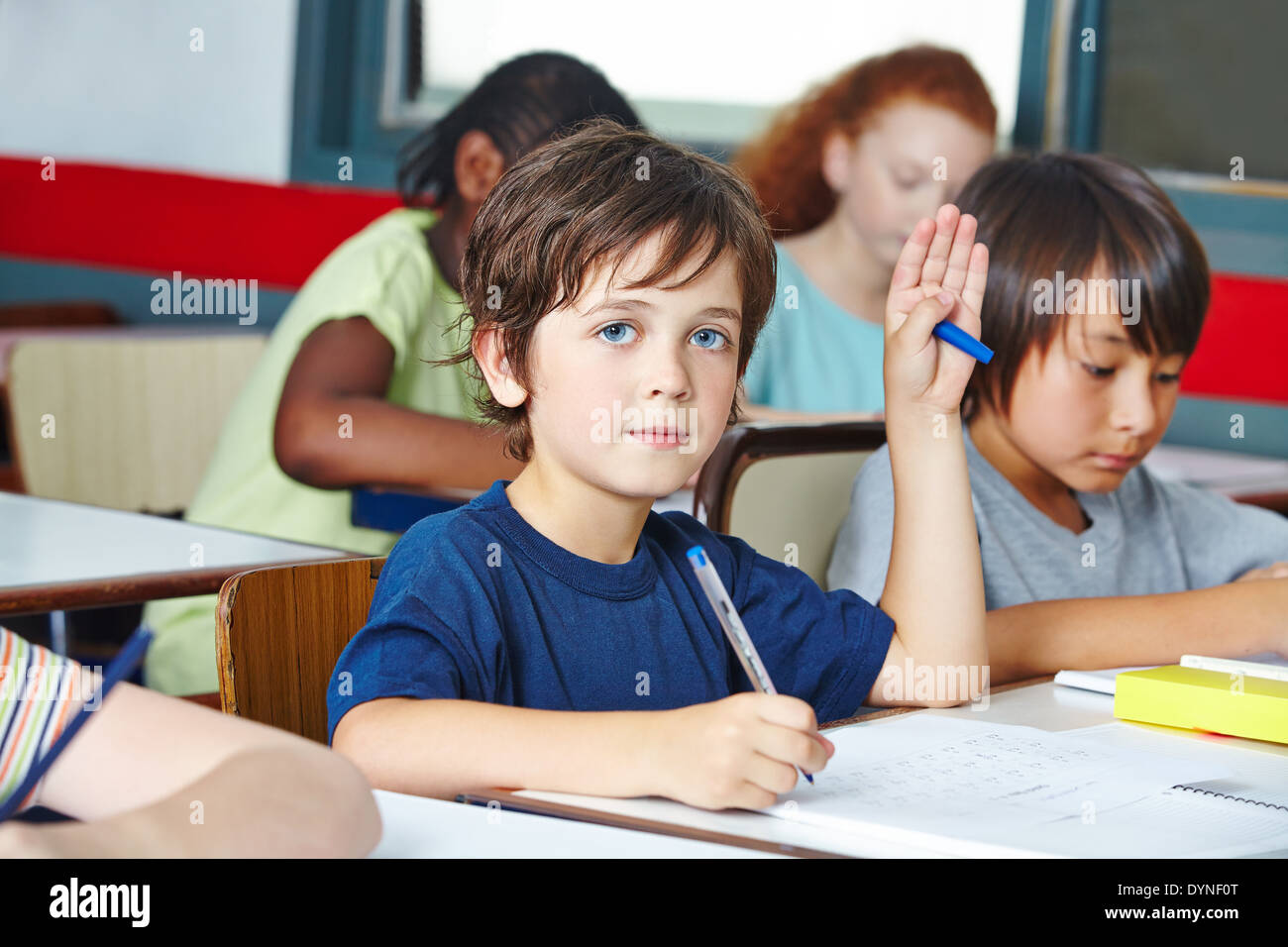 Boy raising his hand in an elementary school class Stock Photo - Alamy