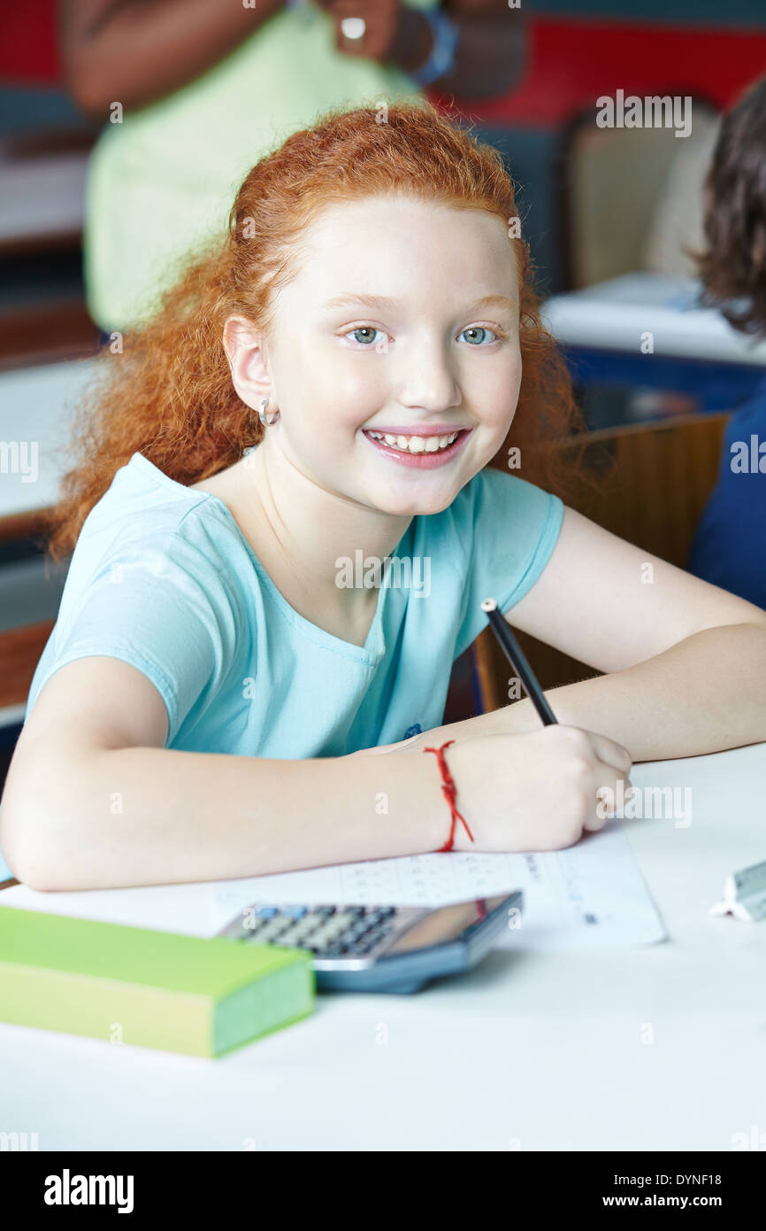 Smiling girl taking notes in elementary school class Stock Photo - Alamy