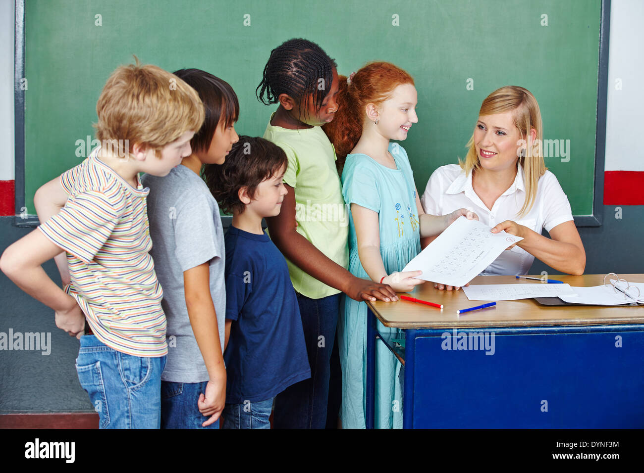 Teacher grading tests for students in elementary school at her desk ...
