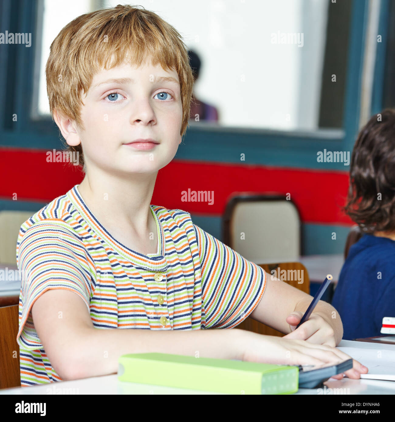 Smiling child in class in elementary school and writing lefthanded ...