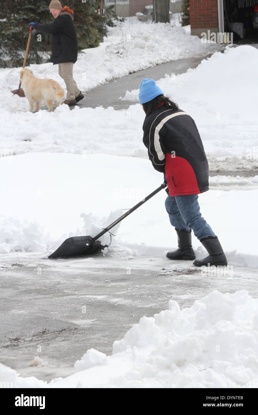 Lady shoveling the deep snow off her driveway after a snow storm Stock ...