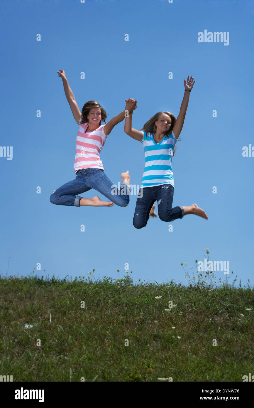 Two teen girls on a hill jumping Stock Photo - Alamy