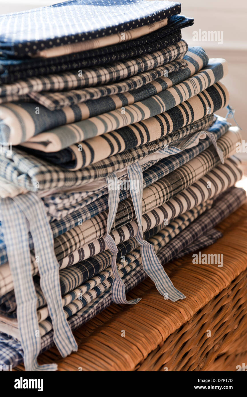 A pile of assorted linens in blue and white stripes and checks folded ...