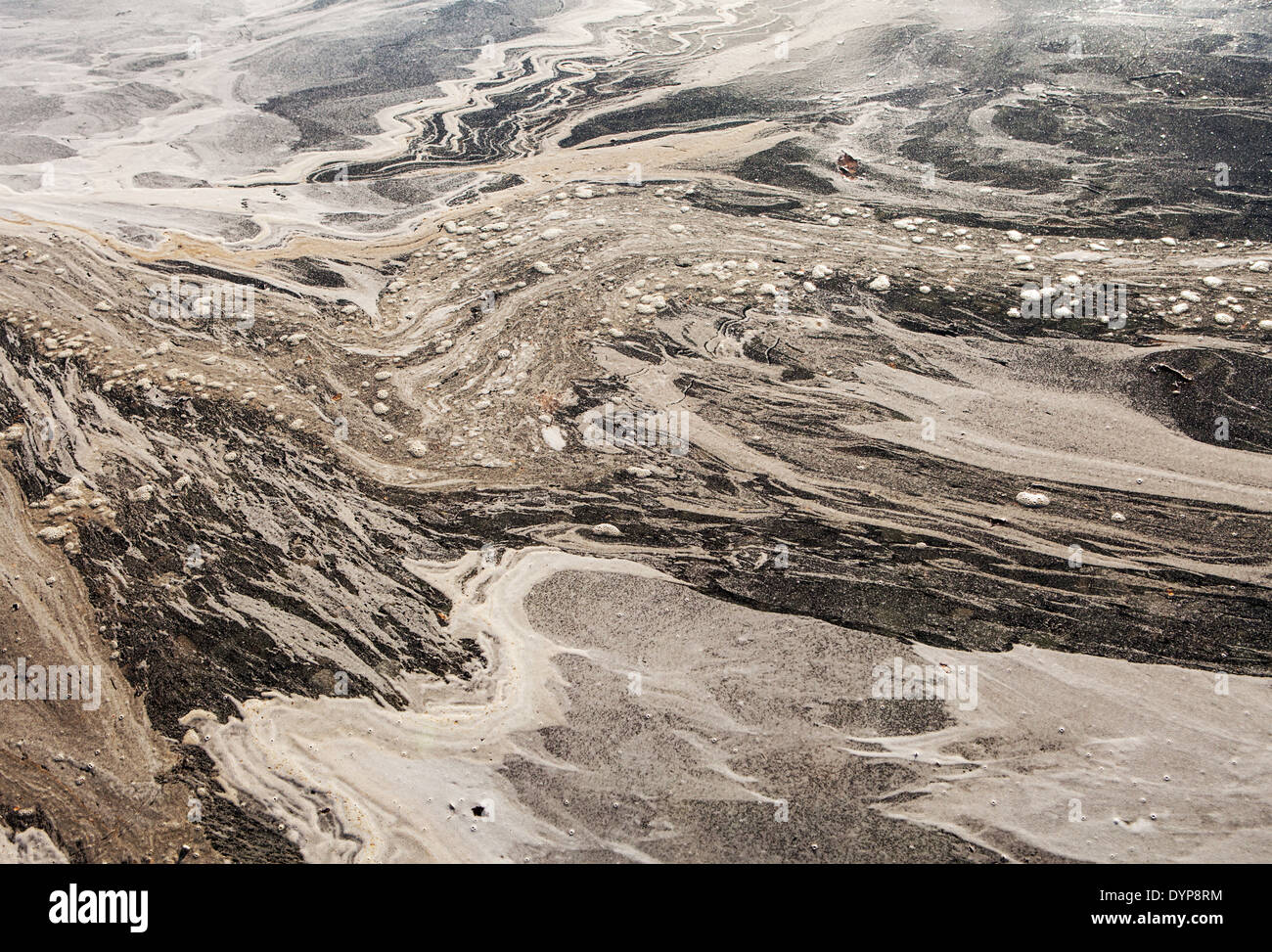 Abstract sea foam patterns formed by waves washing up on a sandy beach ...