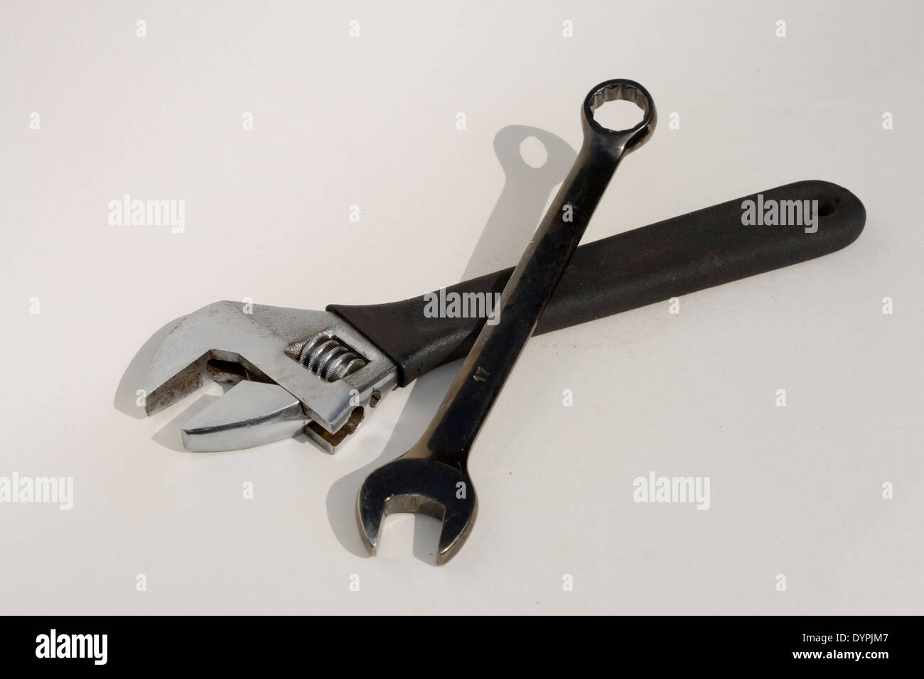 adjustable spanner crossed by a combination spanner on a white back ...