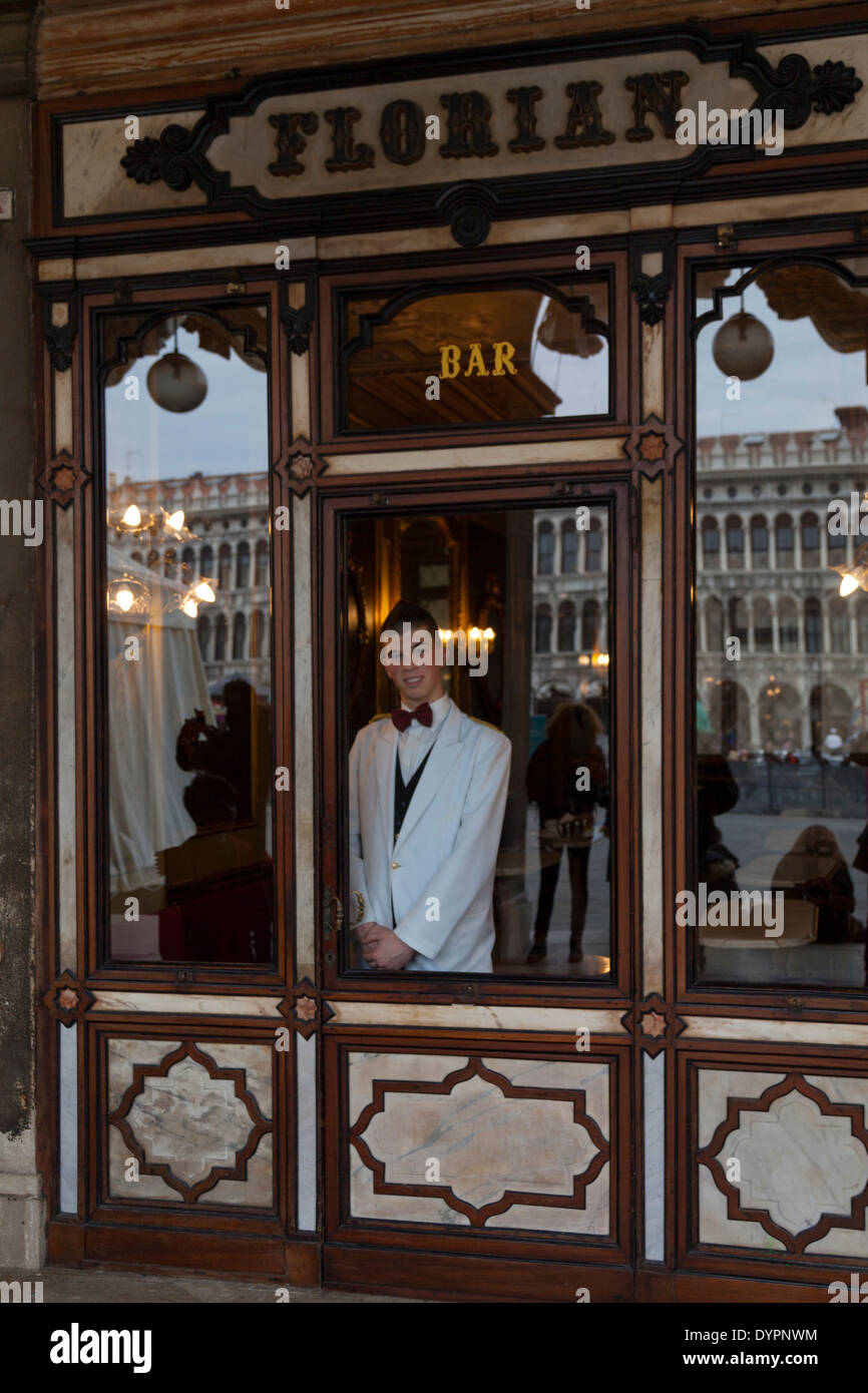 Waiter smiling through the window of the famous Caffe Florian in Venice ...